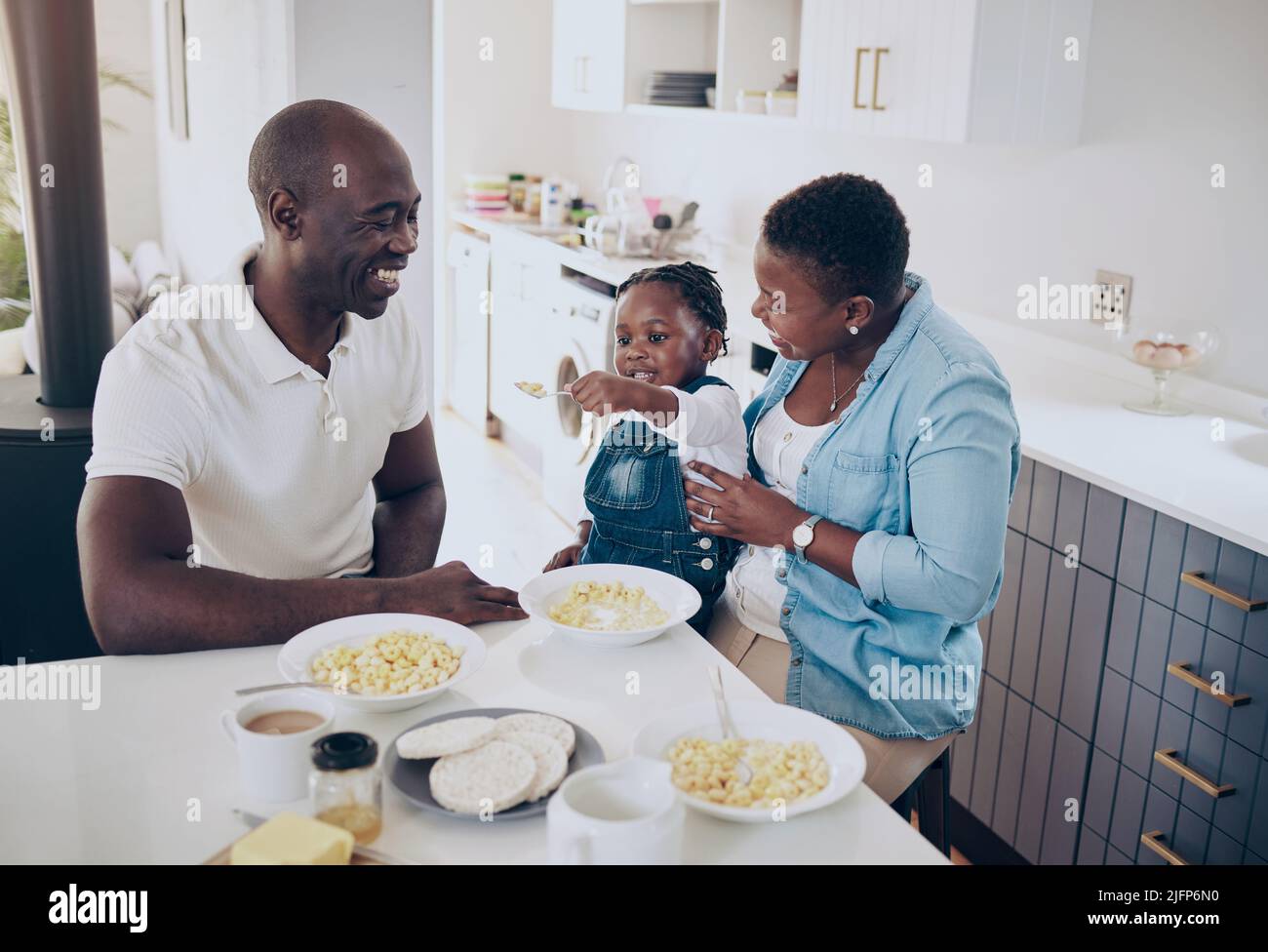 Pure love. Shot of a happy young family bonding while eating breakfast ...