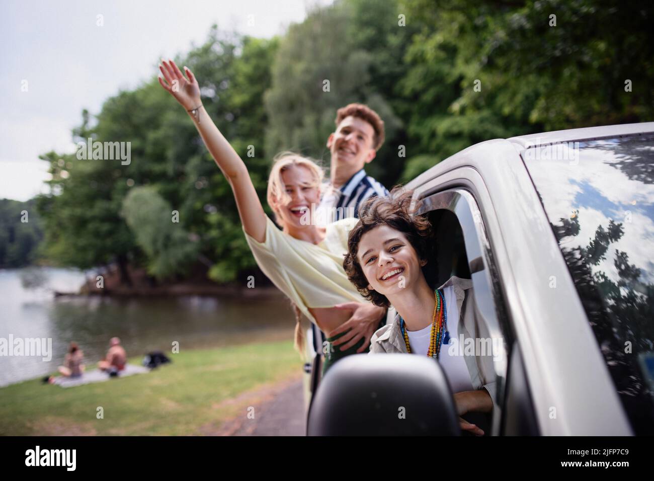 Young friends travelling together by car, looking through window ...