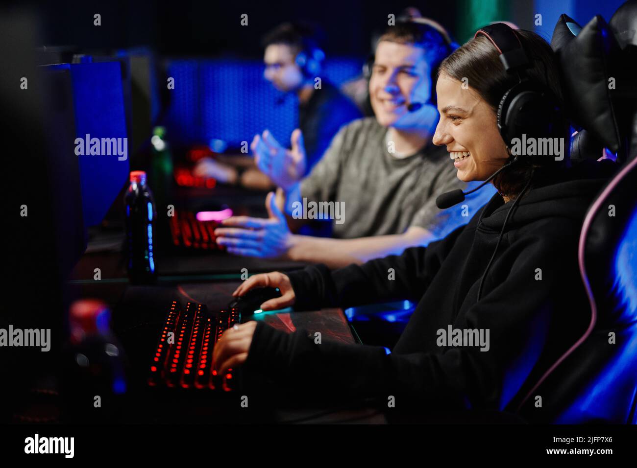 Side view portrait of smiling young woman playing video games on PC ...