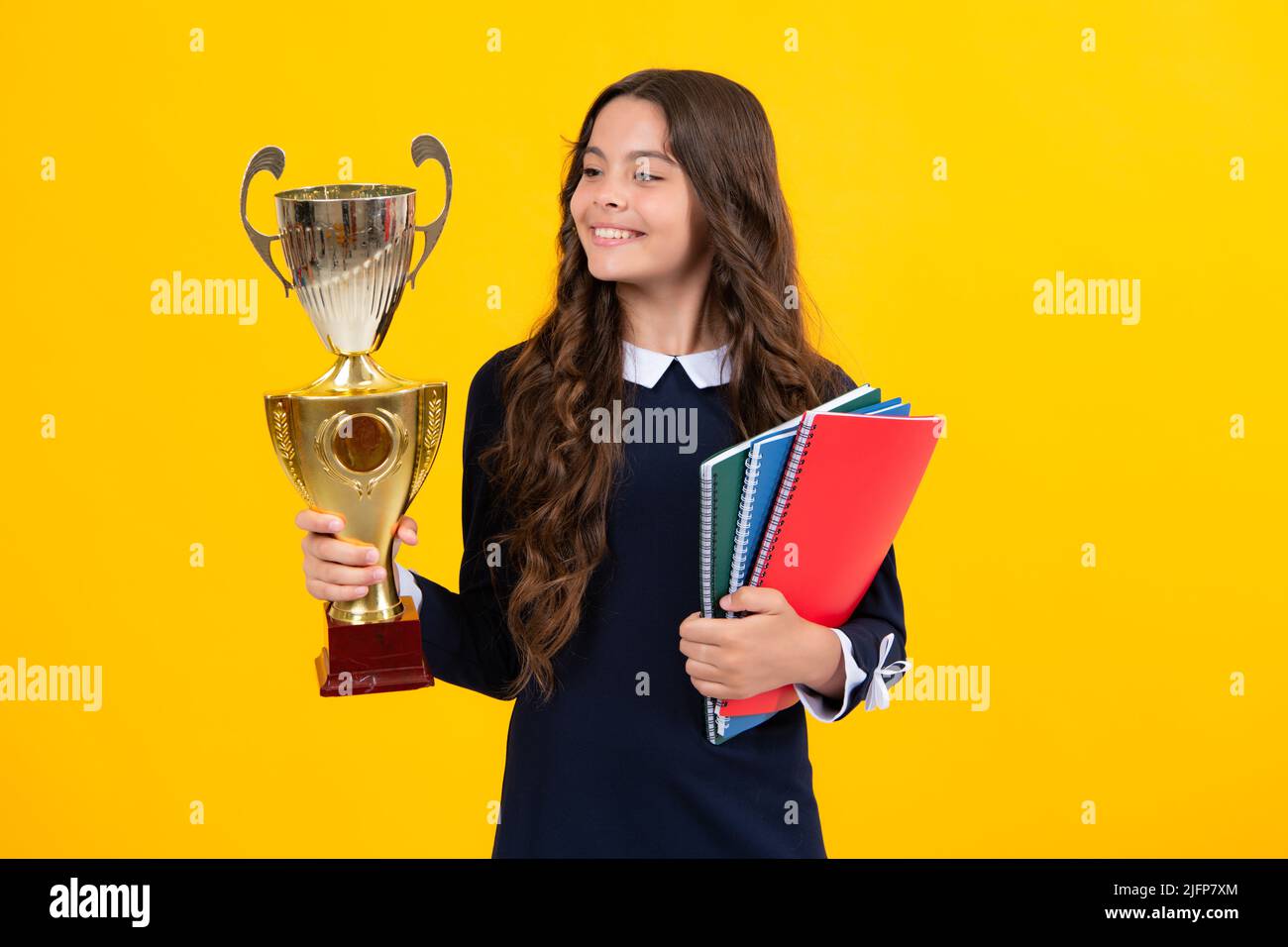 Schoolgirl in school uniform celebrating victory with trophy. Teen ...
