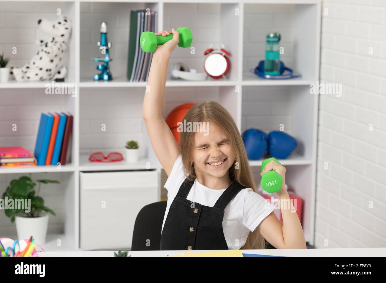 strong child hold barbells in school classroom Stock Photo - Alamy