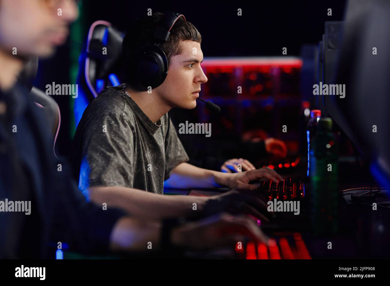 Side view portrait of focused young man playing video game with cyber ...