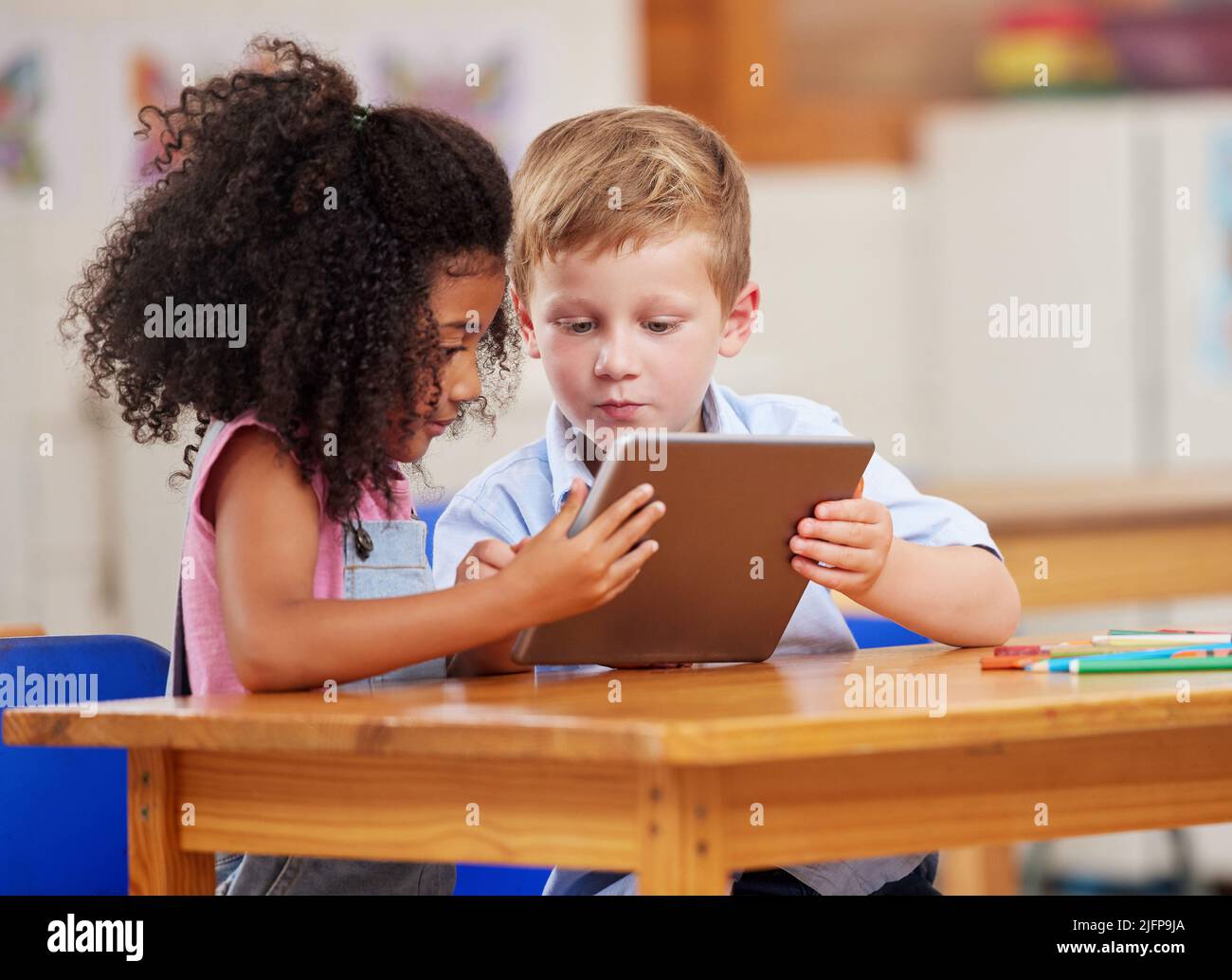 Learning with a little help in the classroom. Shot of two preschool ...