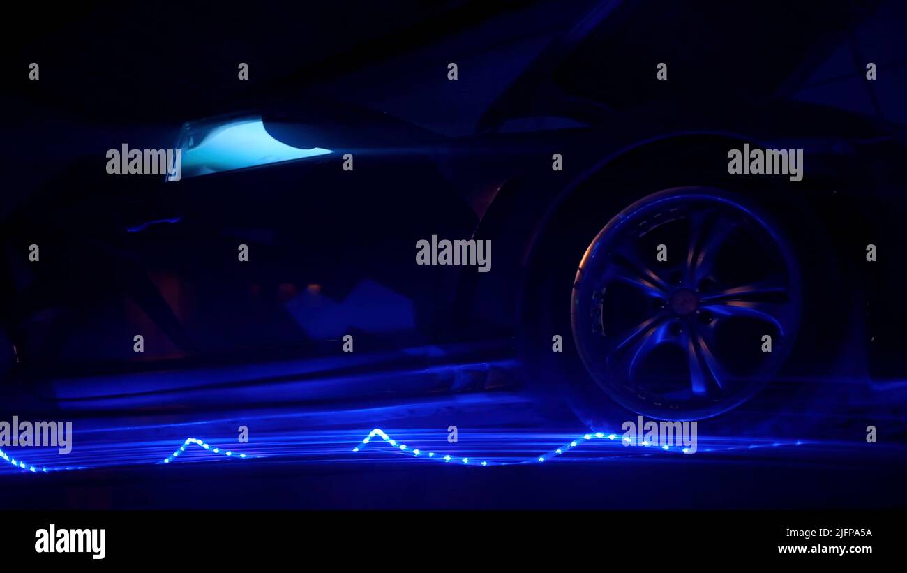 A neon-illuminated car. Clip.A bright black car with neon color around ...