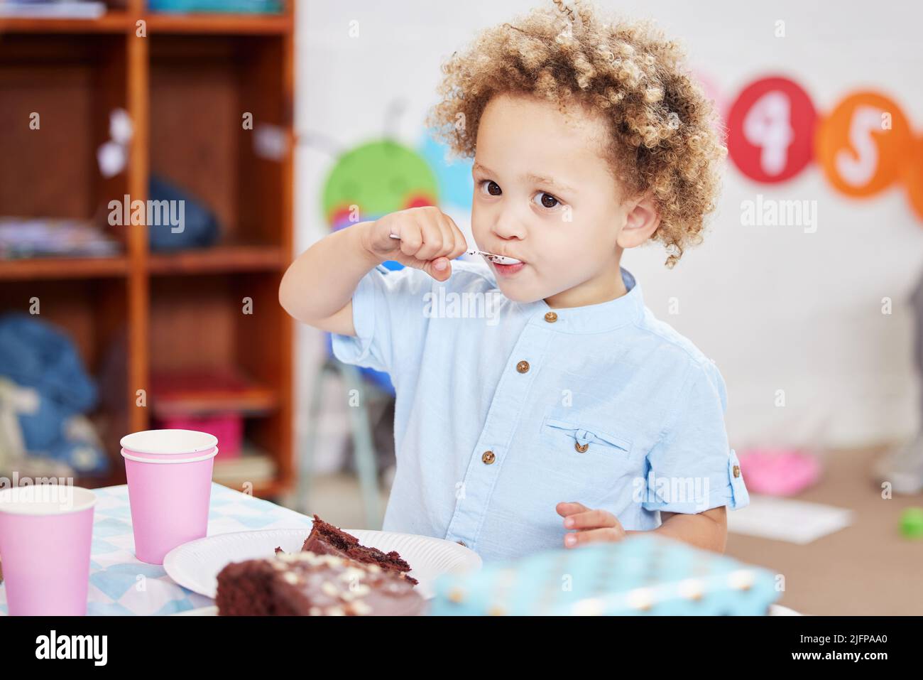 Preschool sure is sweet. Shot of a little boy eating cake in class ...