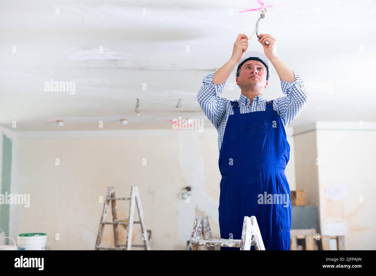 Man electrician standing on stepladder and fixing wires Stock Photo - Alamy