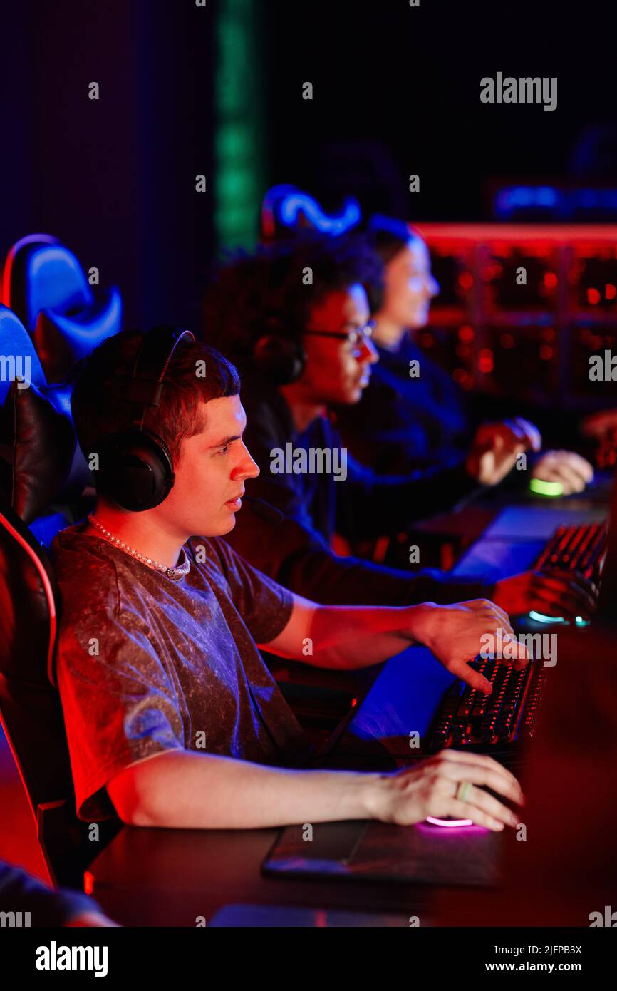 Vertical portrait of diverse eSports team playing video games in row ...