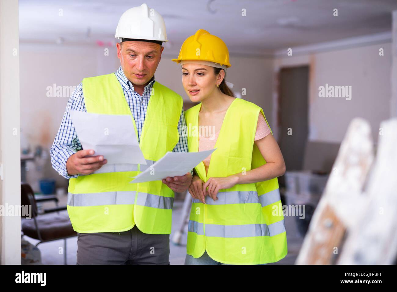 Man and woman builders talking in house Stock Photo - Alamy