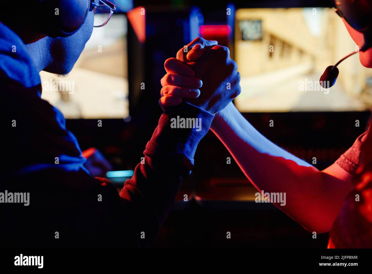 Close up of cyber sports team huddling in unity with video game screens ...