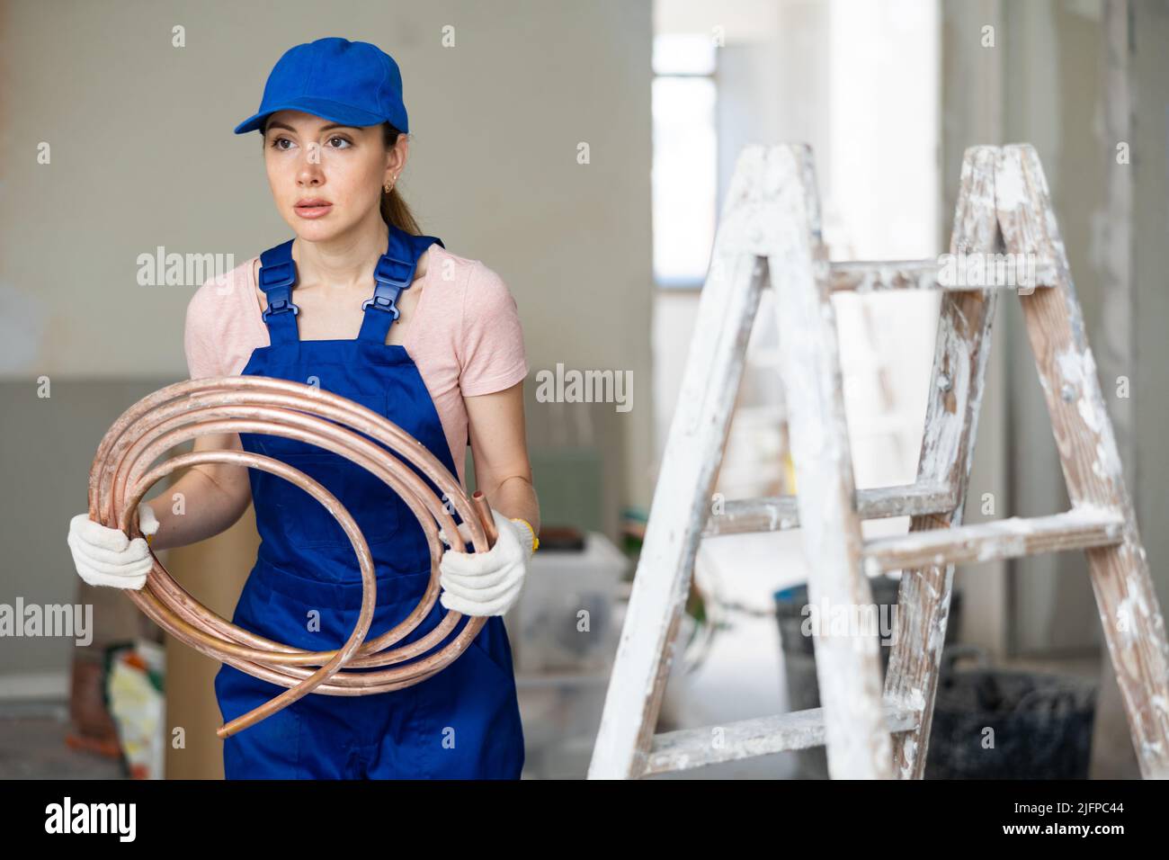Female builder carrying conduit at renovating object Stock Photo - Alamy
