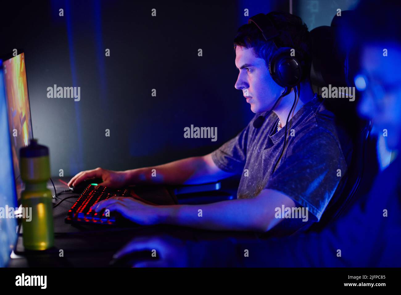 Side view portrait of man playing video games in cybersports club lit ...