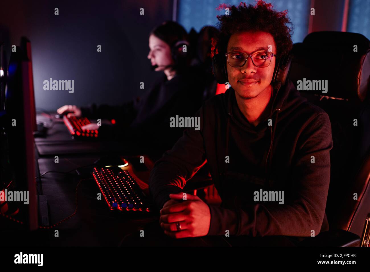Portrait of black young gamer looking at camera in red neon light and ...