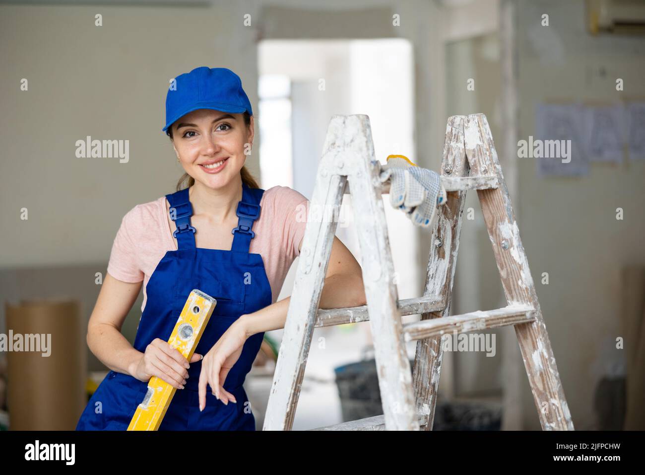 Portrait of builder woman in blue overalls with building level Stock ...