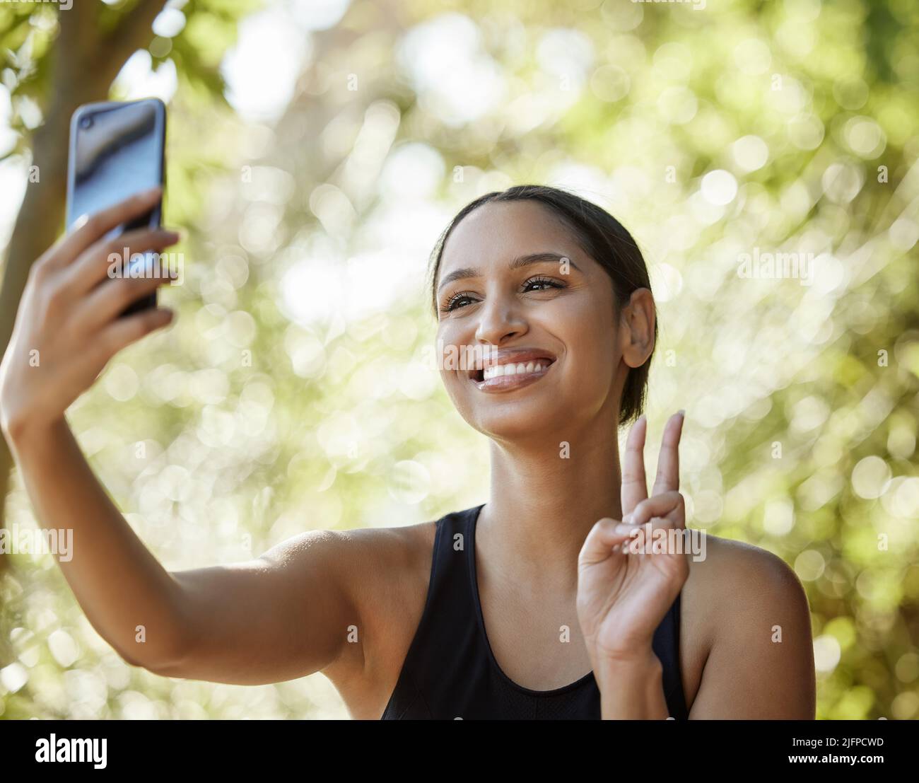 Selfies in the sun. Cropped shot of an attractive young female athlete taking selfies while ...