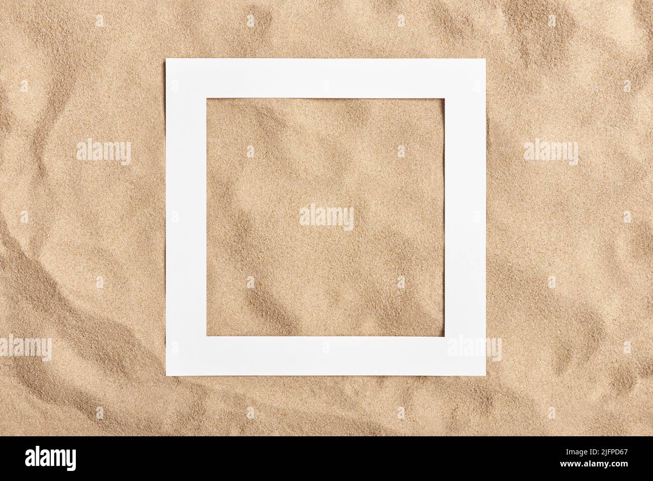 Summer layout, flat lay of beach sand with an empty white paper frame ...
