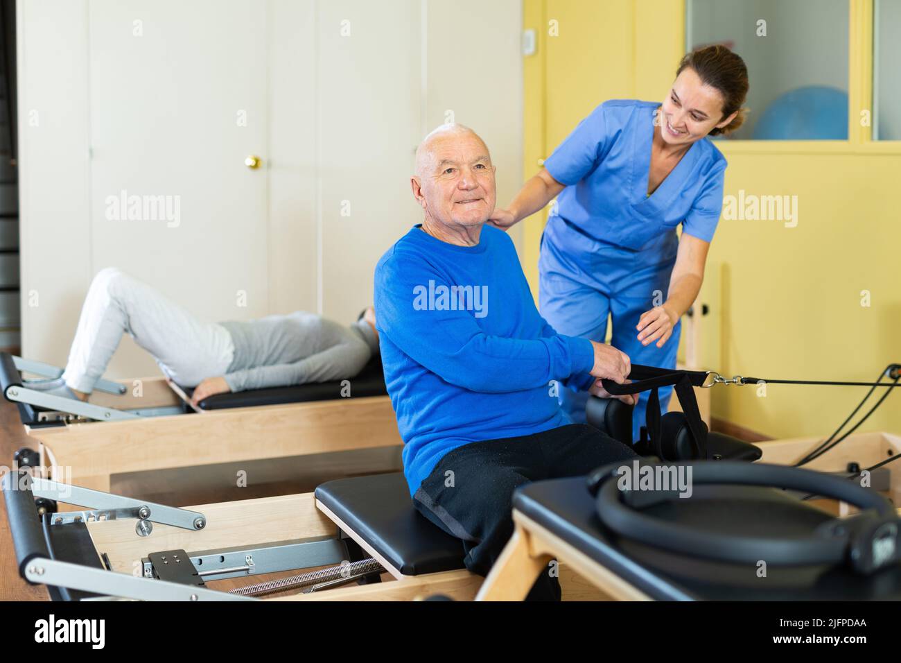 Medical professional helps and monitors the difficulty of Pilates ...