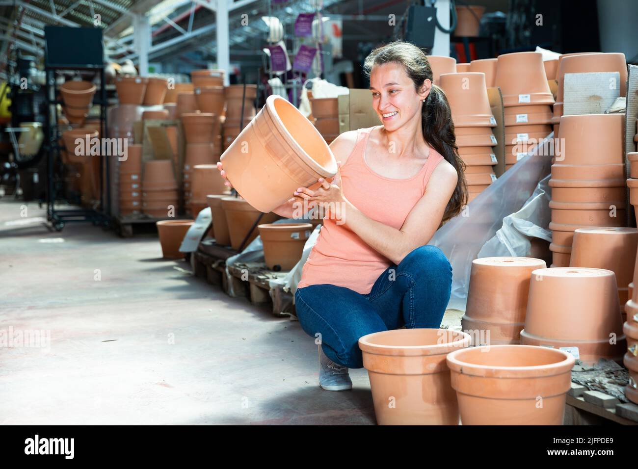 Positive woman customer holding small decorative clay pot for flowers ...