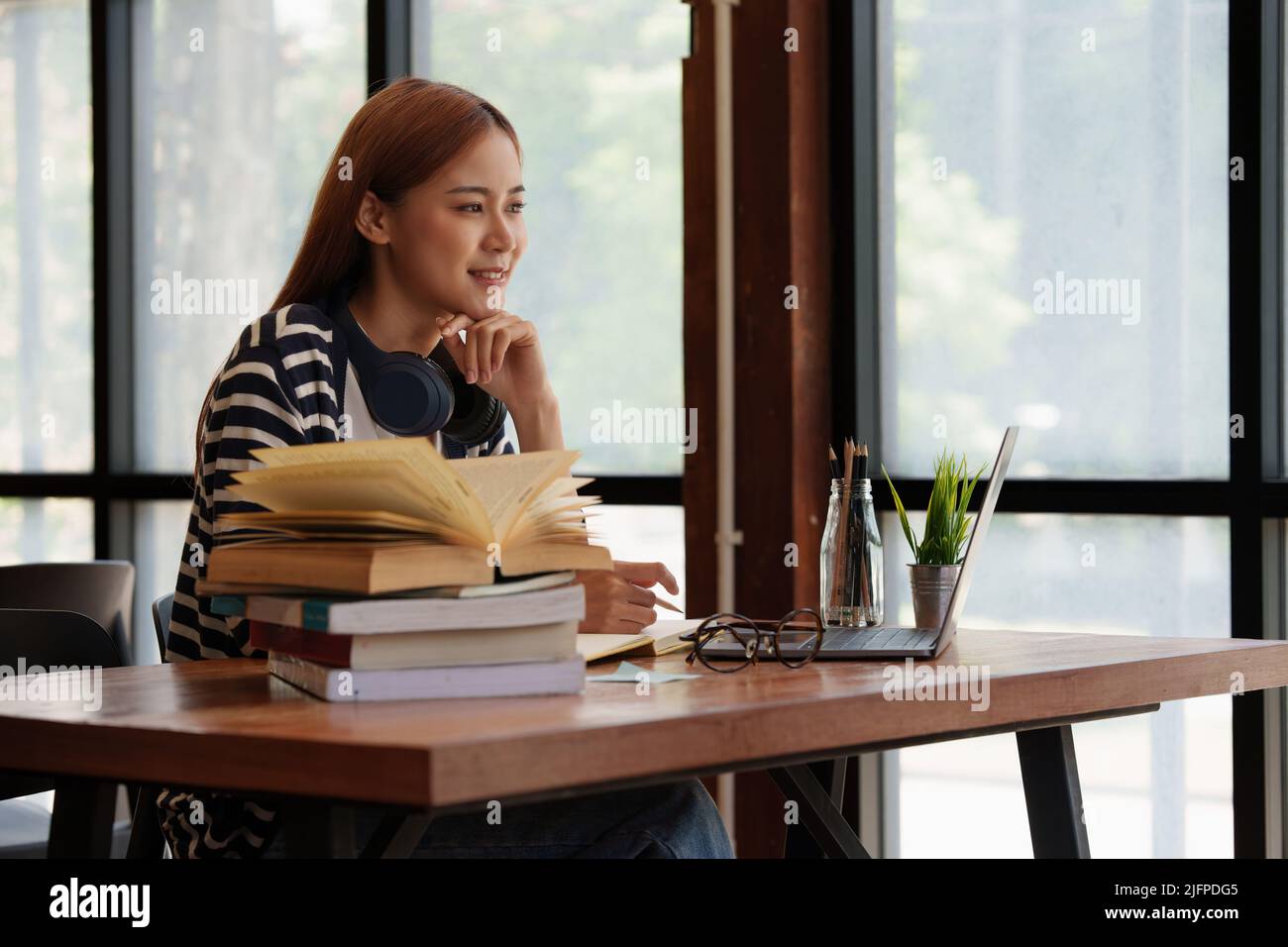 Young asian girl student wear headphone and writing a notebook and ...