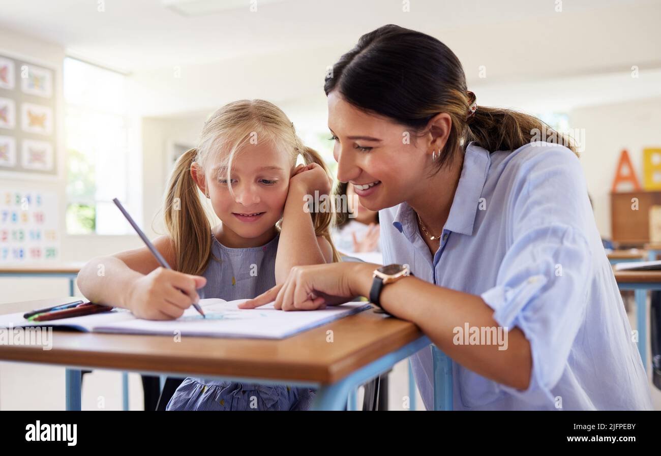 Paying attention in class. Shot of a female teacher assisting a ... Paying attention in class. Shot of a female teacher assisting a ...