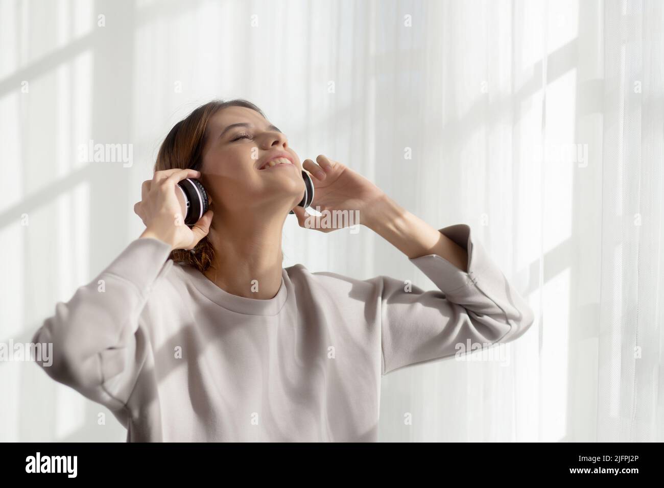 Happy young asian woman wearing headphones listening music while ...