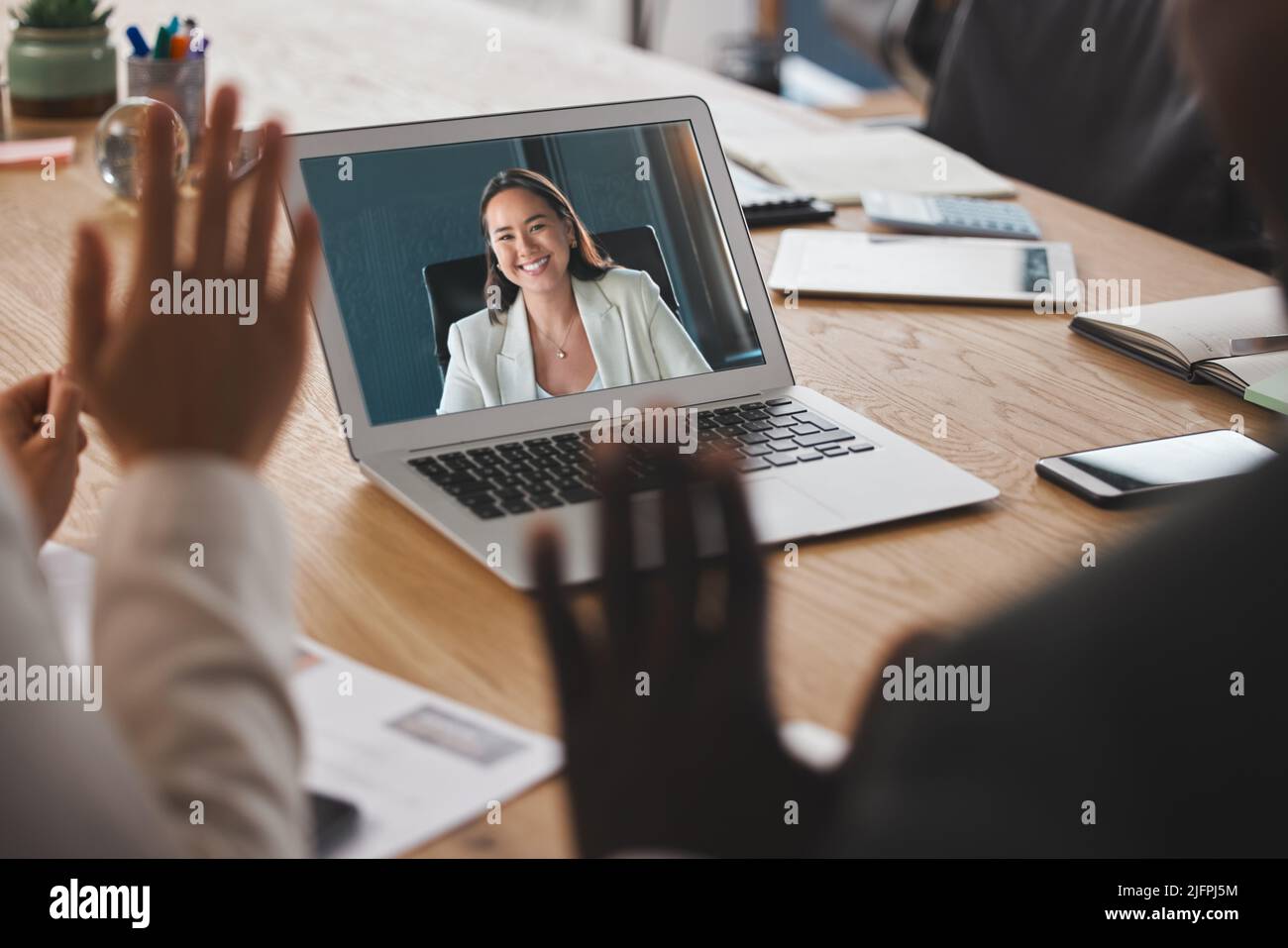 Staff waving to happy young asian businesswoman shown on laptop screen ...