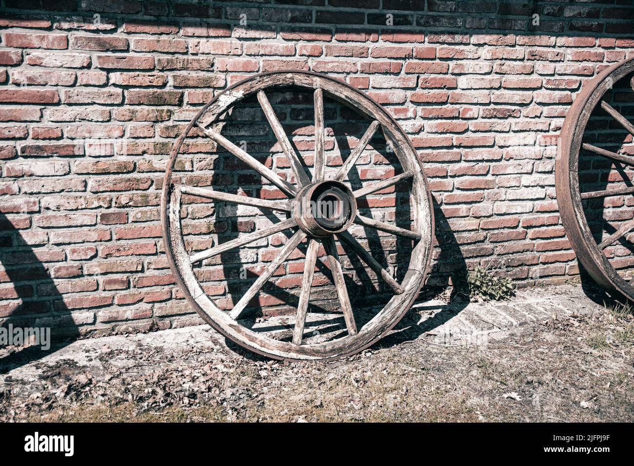 A Large wagon wheel against a brick housewall Stock Photo - Alamy