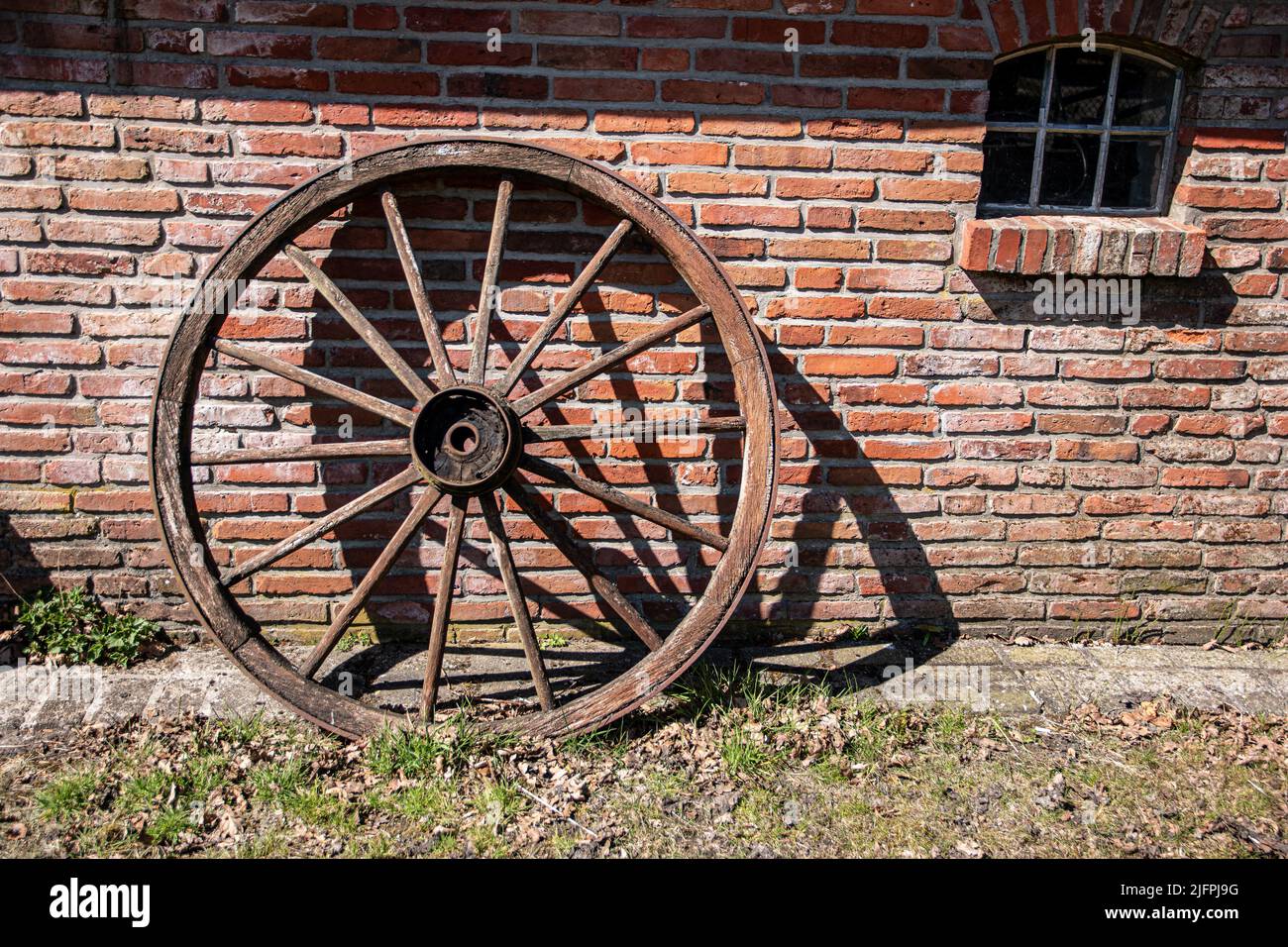 A large wagon wheel against a brick house wall Stock Photo - Alamy