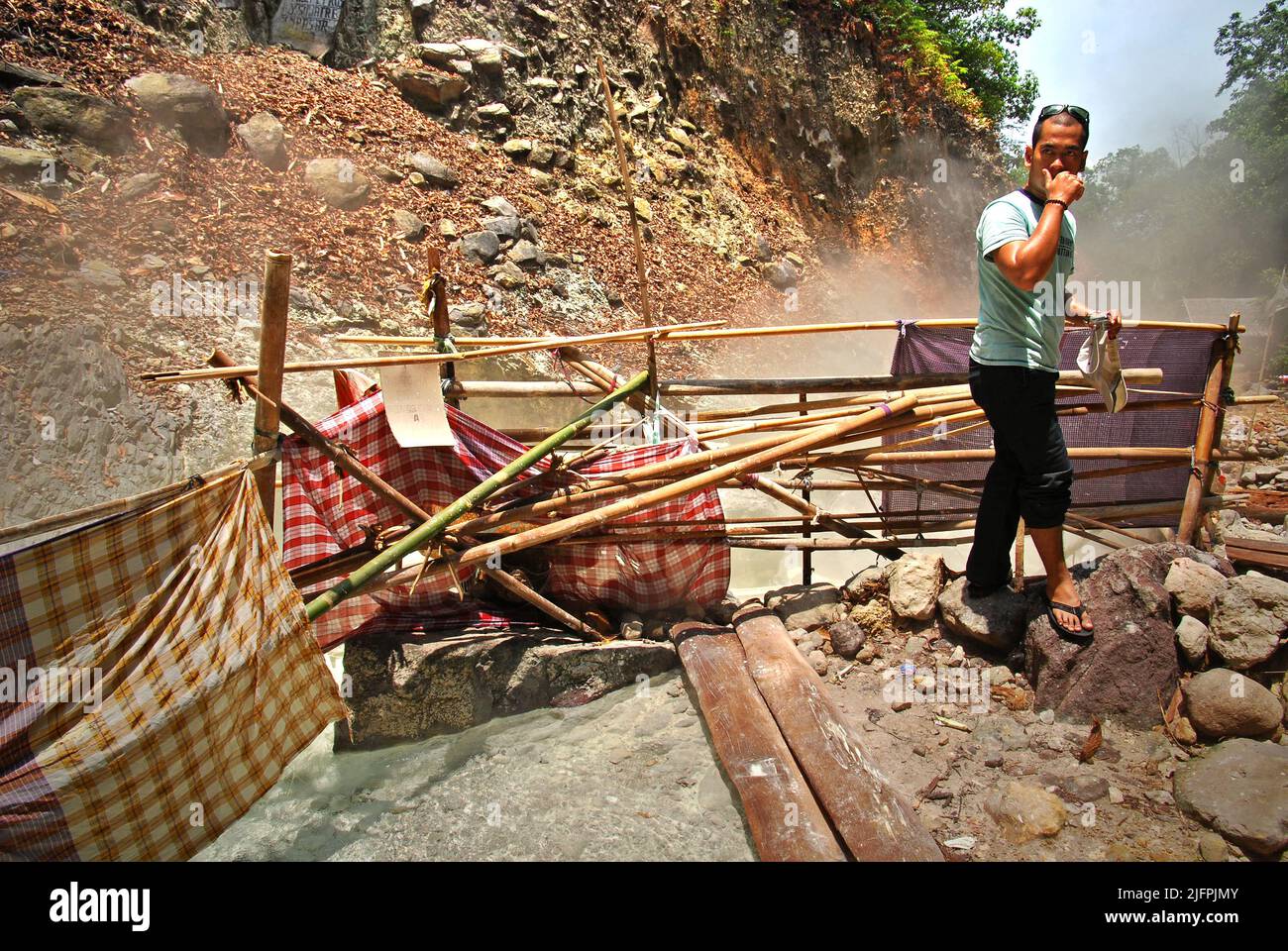 A visitor standing on the side of a hot spring at the foot of Mount ...