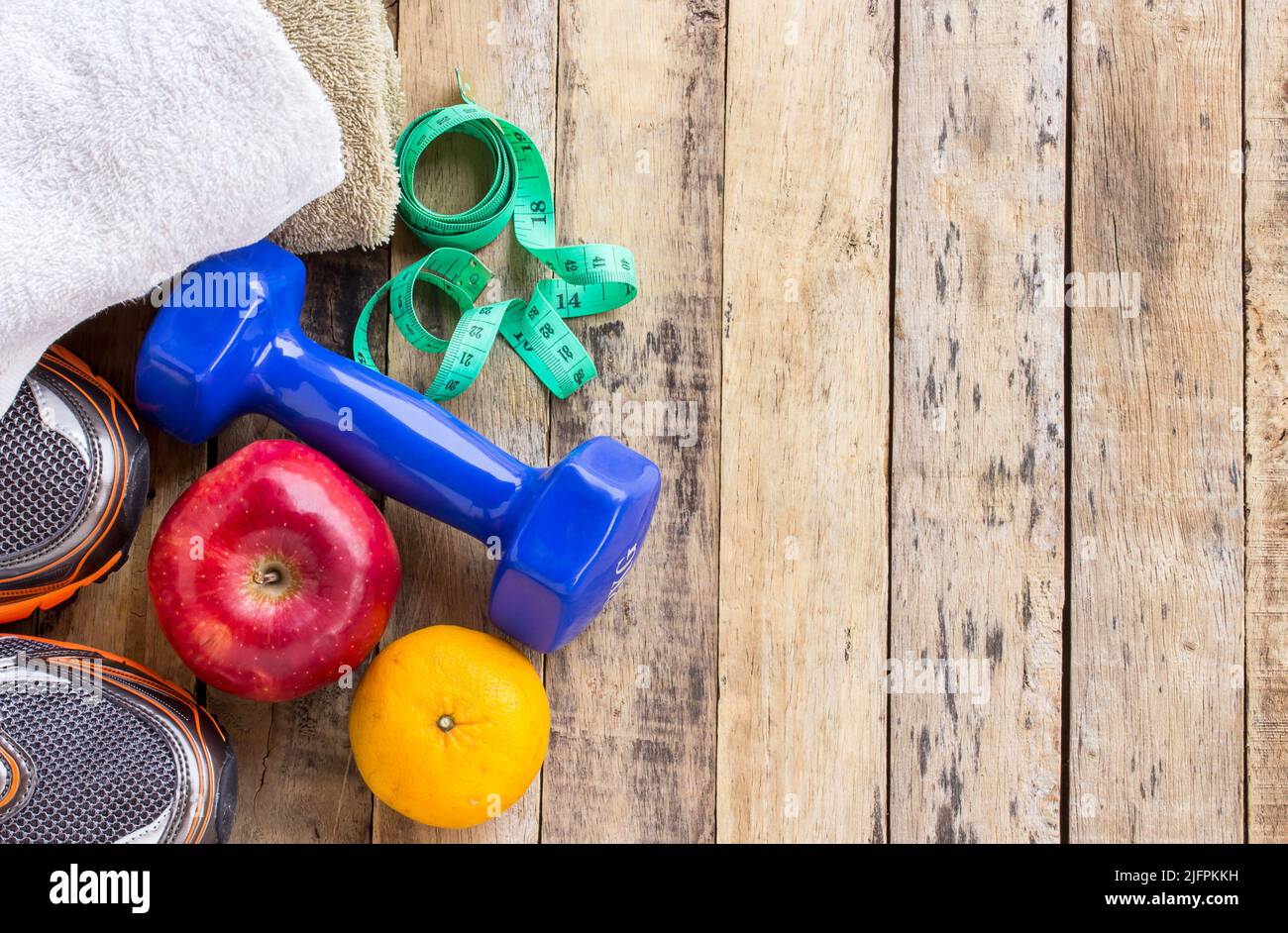 Blue dumbbell, white towel, measuring tape and red apple on wooden ...
