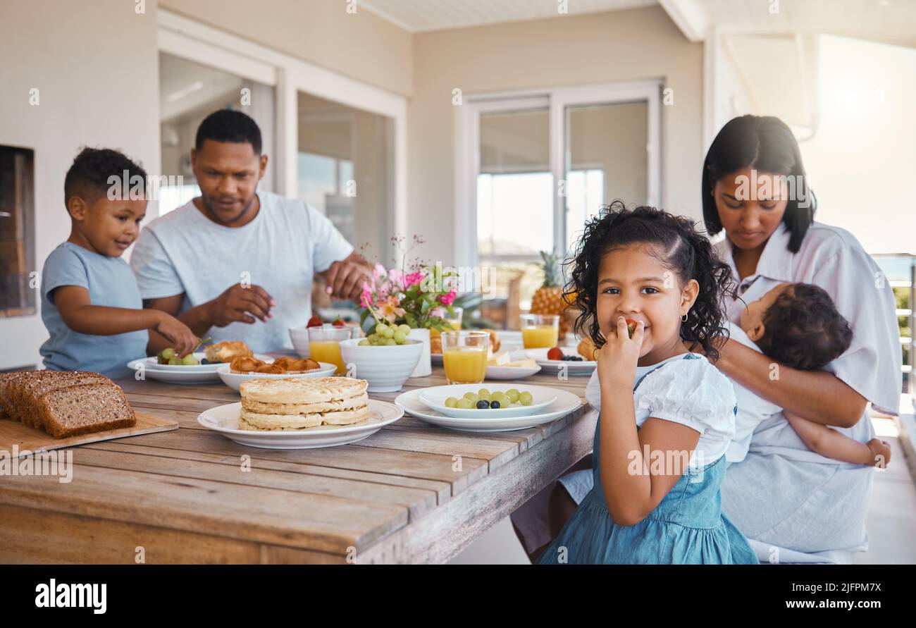 Happy, healthy girl. Shot of a young family having lunch together at ...