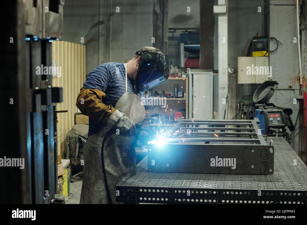 Side view of male worker of huge industrial plant or manufactory ...