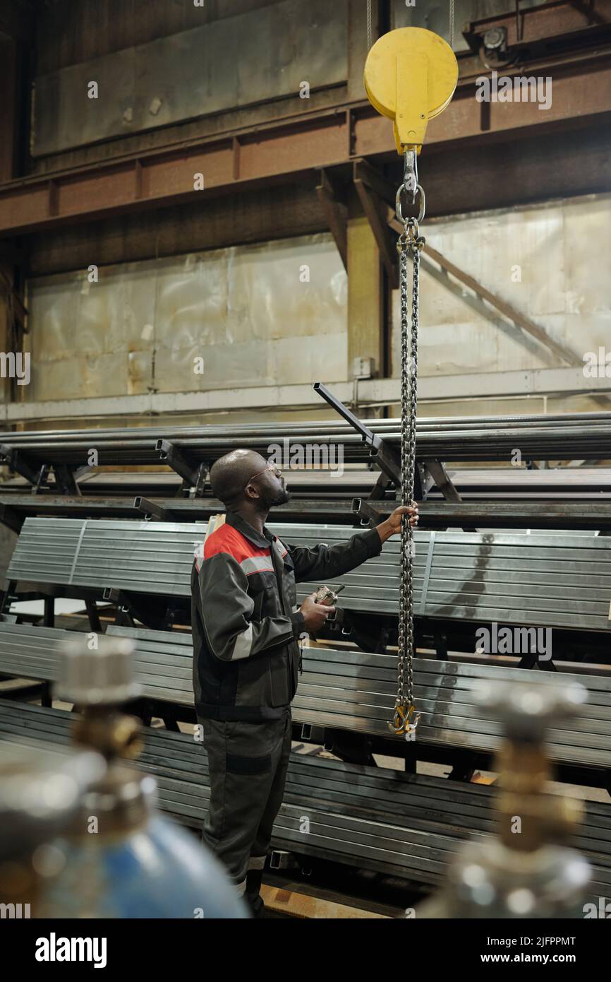Young black man pulling bunch of metallic chains while standing in ...