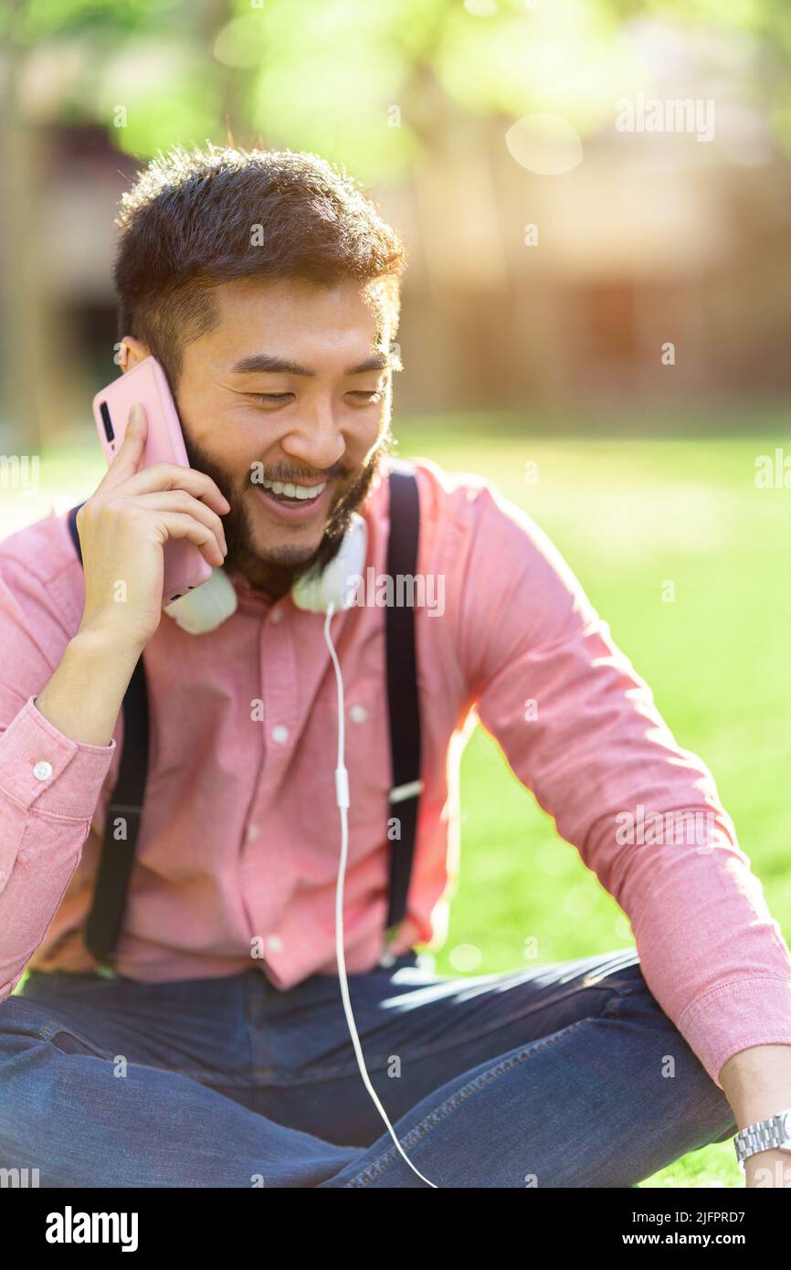 Asian man laughing while talking on his mobile phone Stock Photo - Alamy