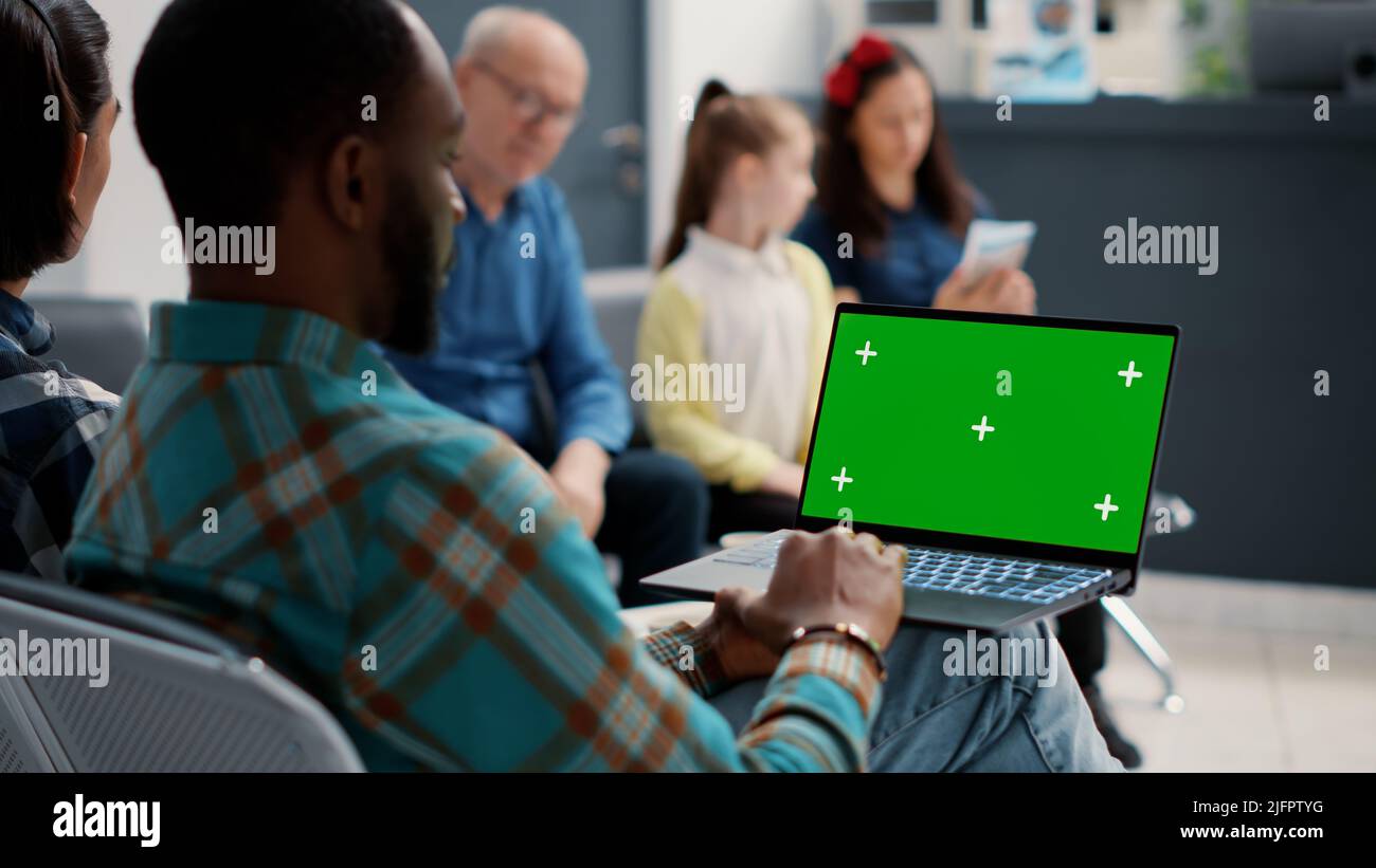 African american man using laptop with greenscreen on display in ...