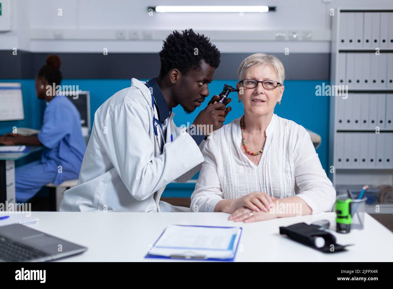 Polyclinic otologist consulting senior patient using otoscope to check ...