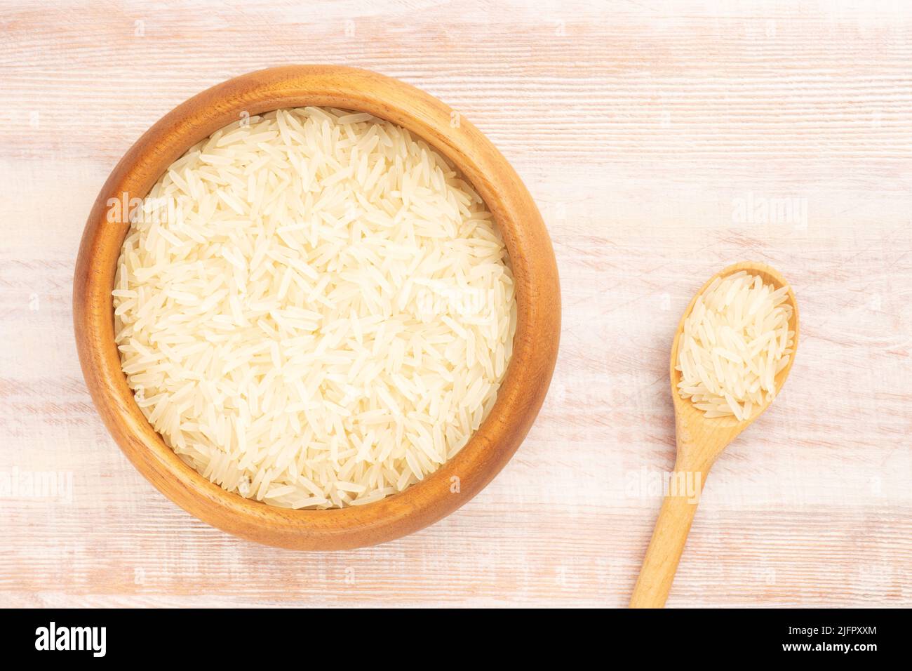 Long Basmati rice in wooden bowl and spoon on brown wooden background ...