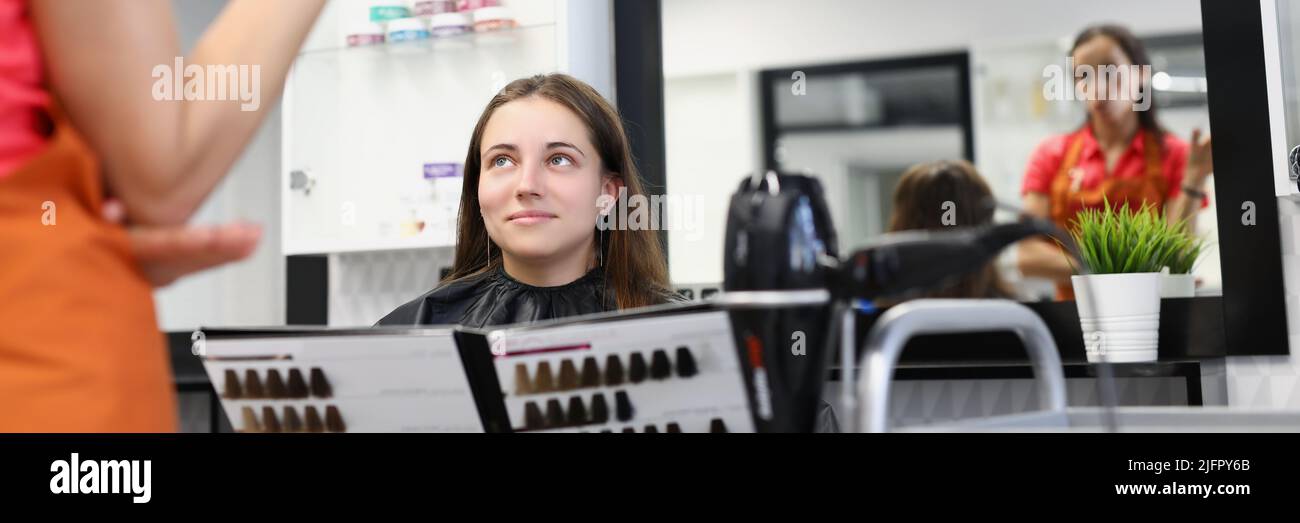 Pretty woman client hold palette of colours for hair dye at hairdresser ...