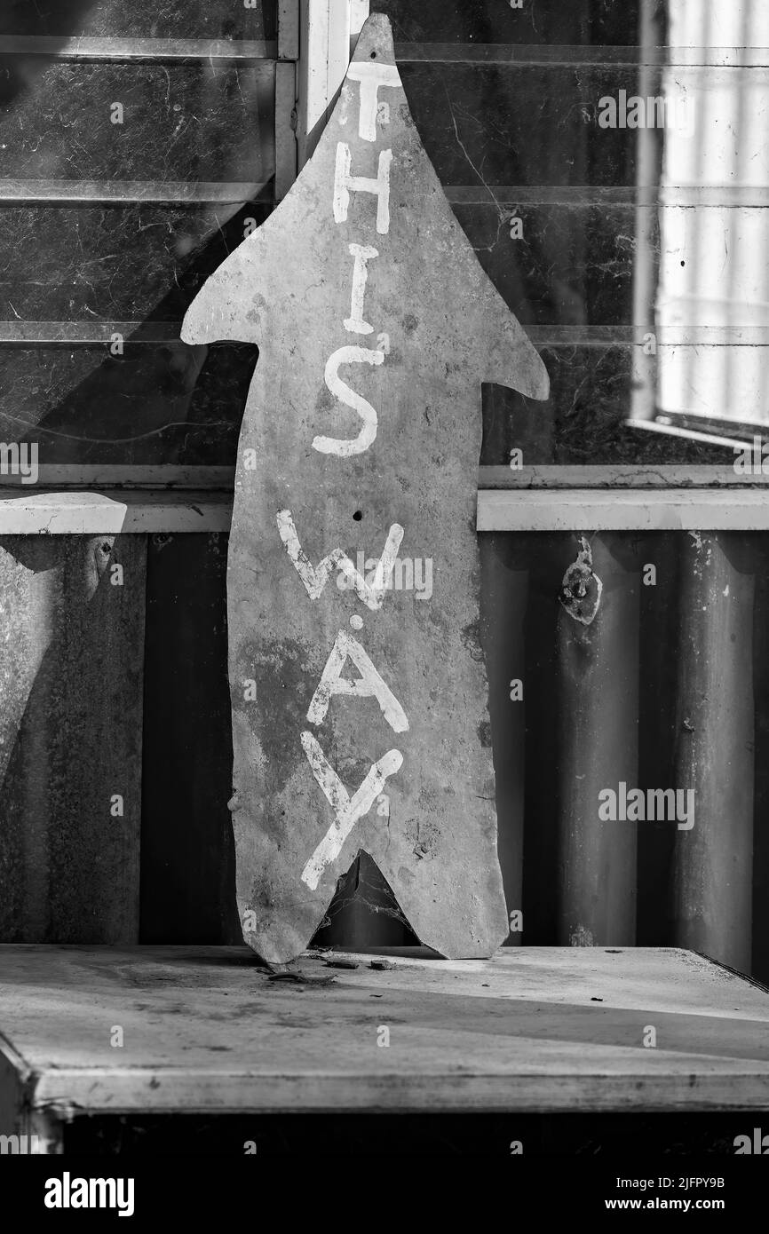 Old wooden arrow sign saying "This Way" propped against the wall of an ...