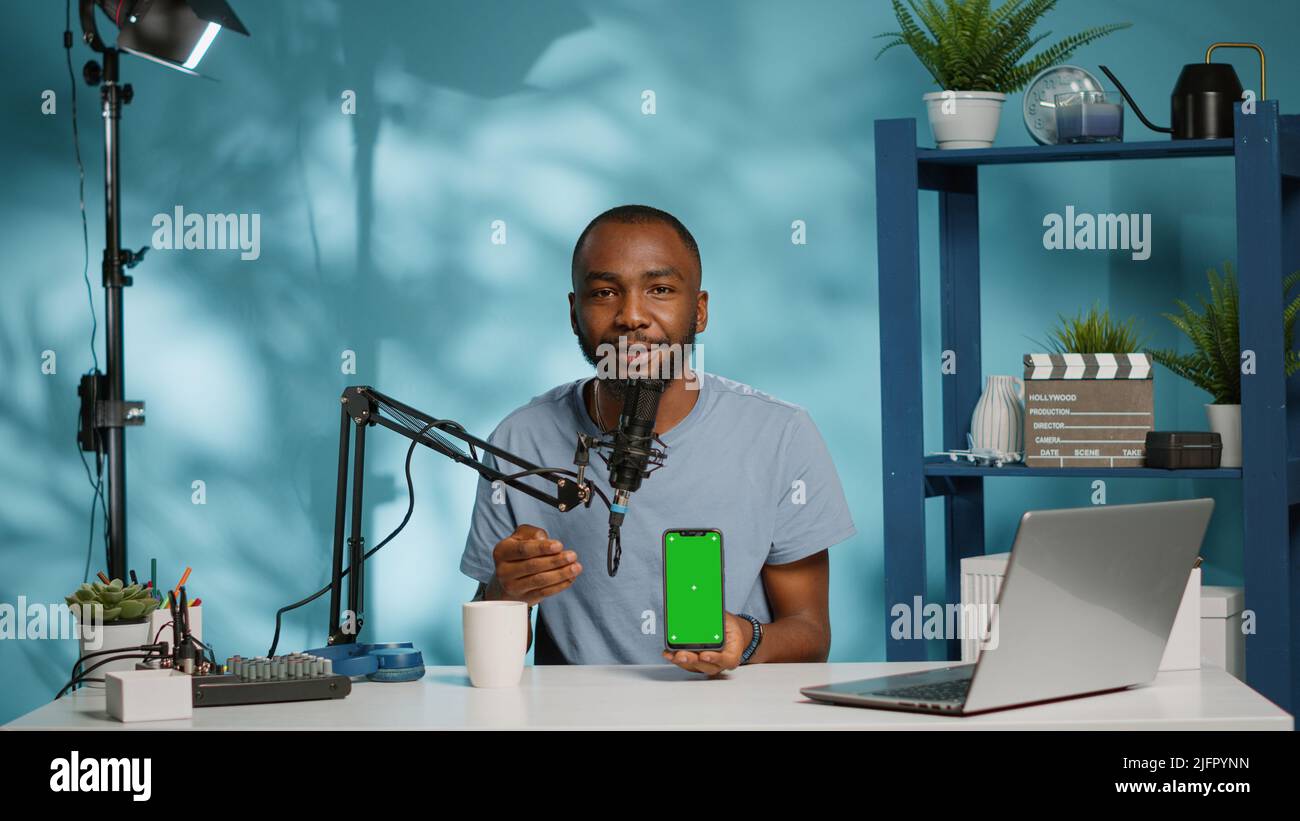 Influencer holding smartphone with green screen on display while ...