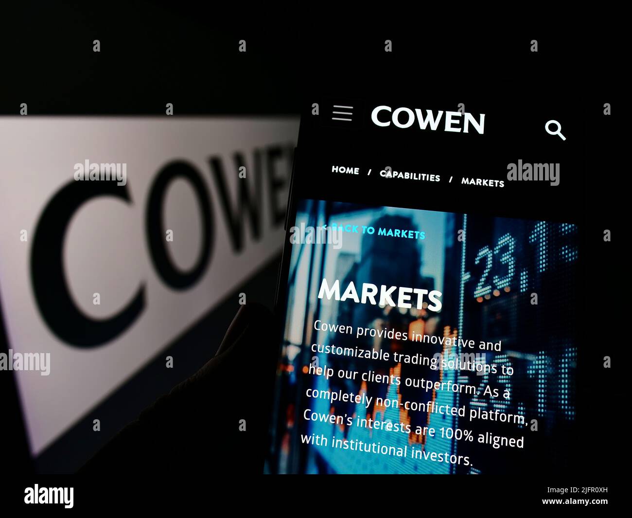 Person holding cellphone with webpage of US investment banking company ...