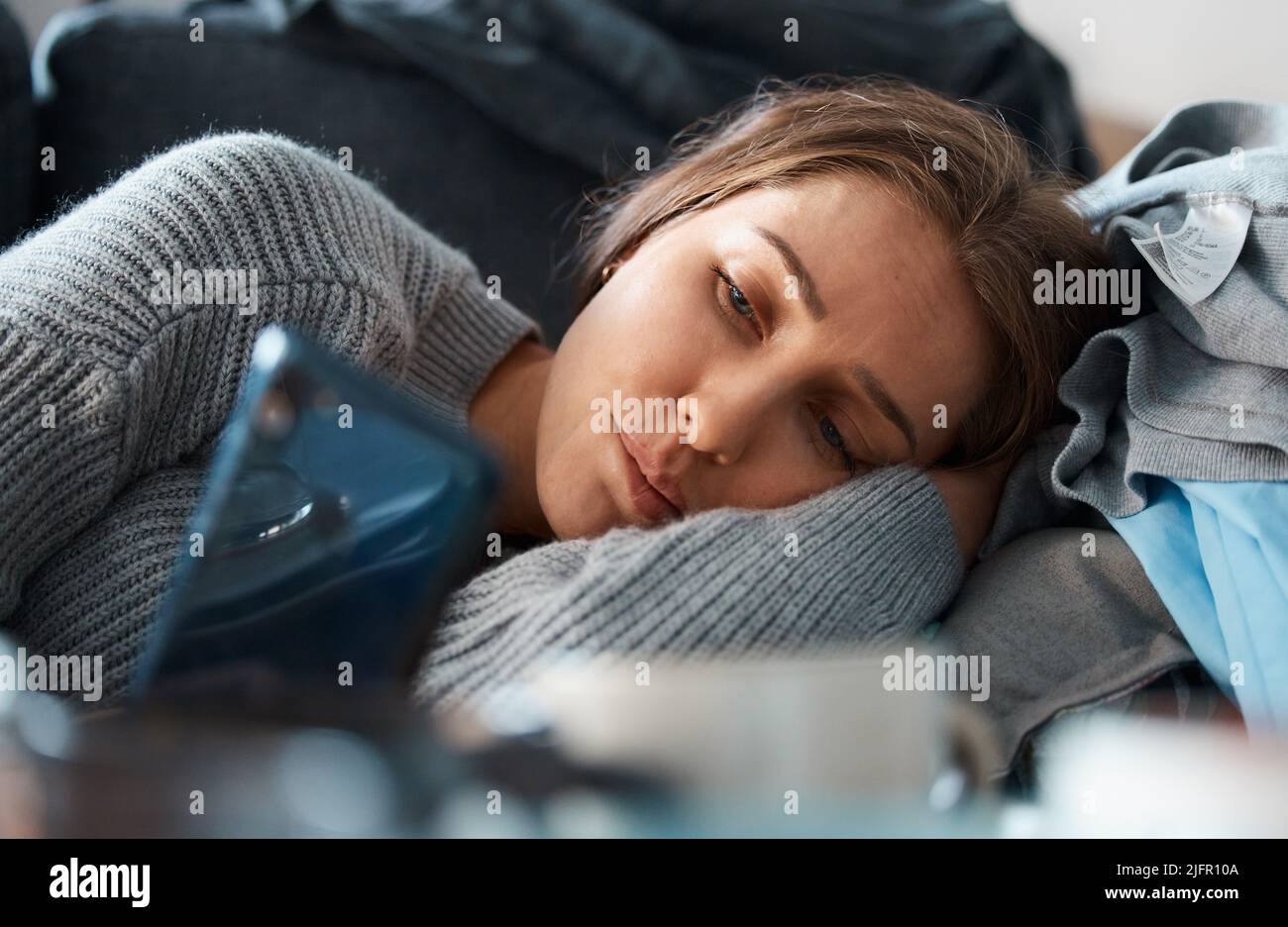 Why hasnt he texted me. Shot of a young woman looking depressed while ...