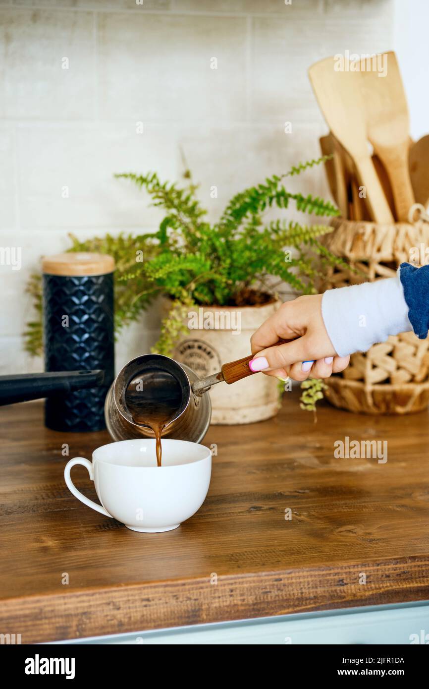 Closeup view of hand pouring coffee in a cup. Morning routine concept ...
