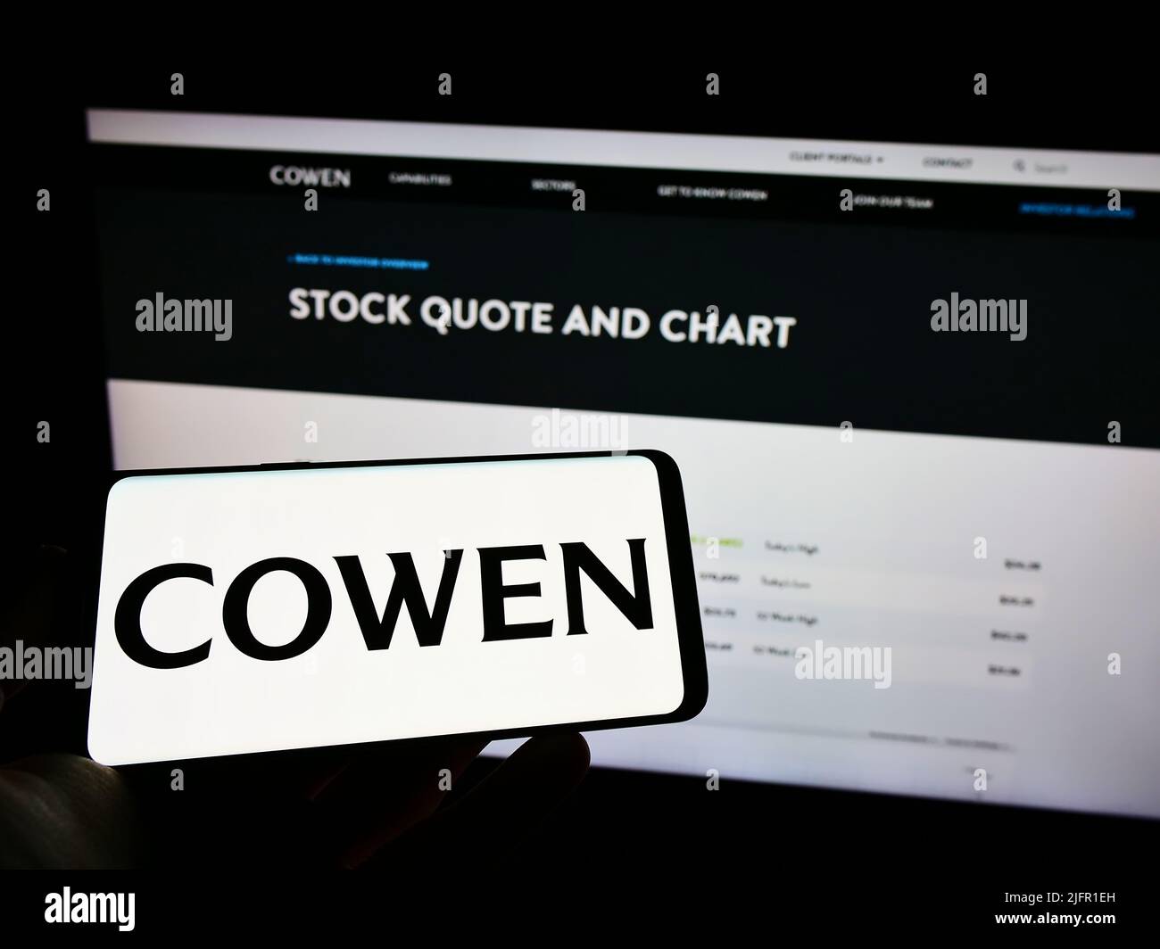 Person holding mobile phone with logo of American investment banking ...