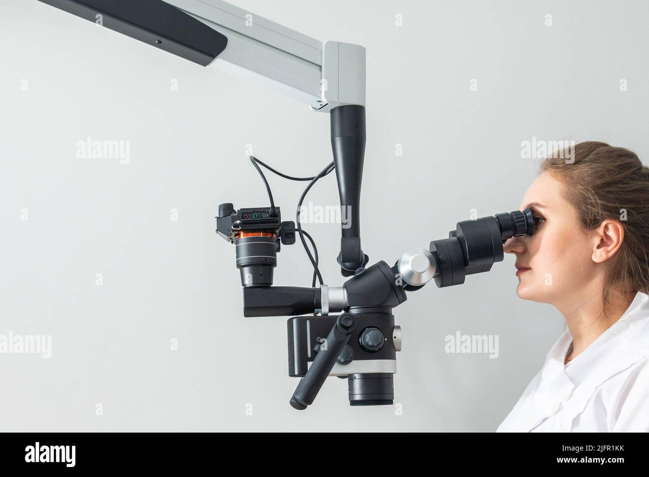 Female dentist using dental microscope treating patient teeth at dental ...