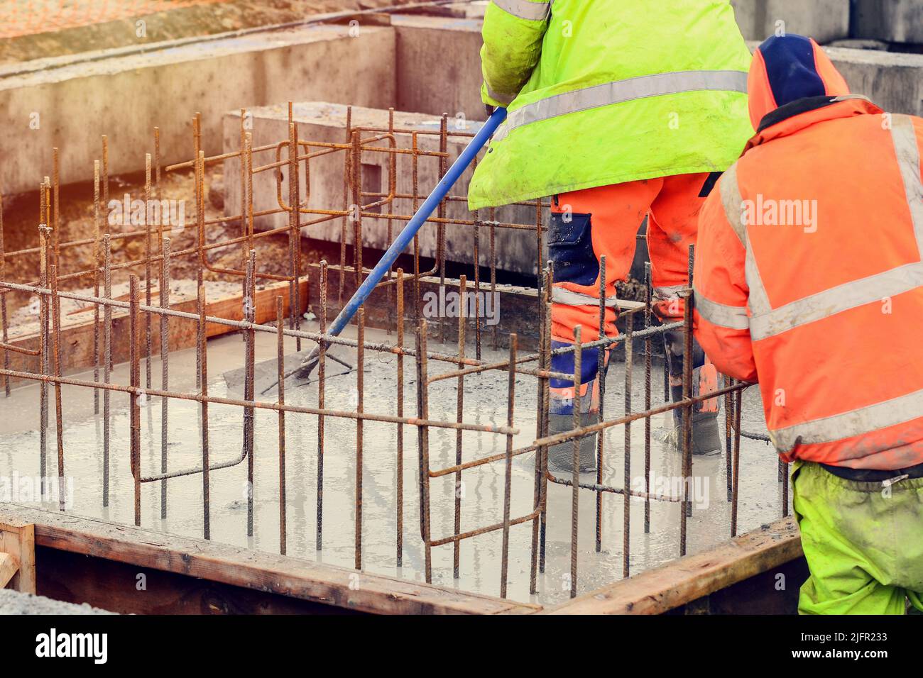 Pouring wet ready-mix concrete into lift pit base and levelling it ...
