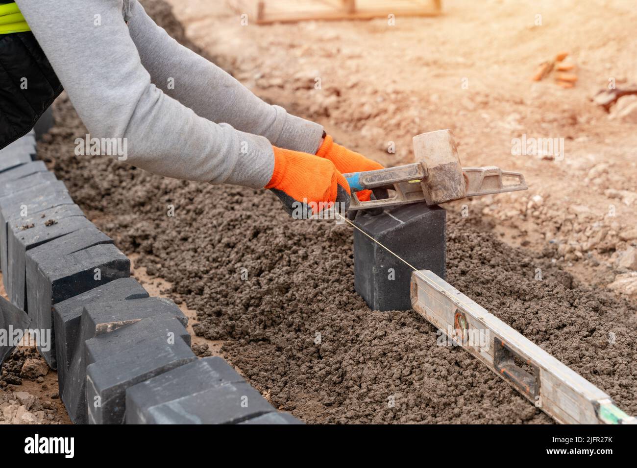 Builder installing paving blocks during road and footpath construction ...