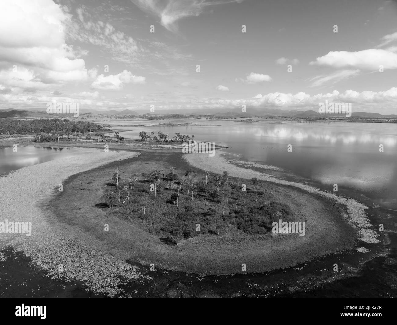 Drone aerial above a patch of land in a dam surrounded by aquatic ...
