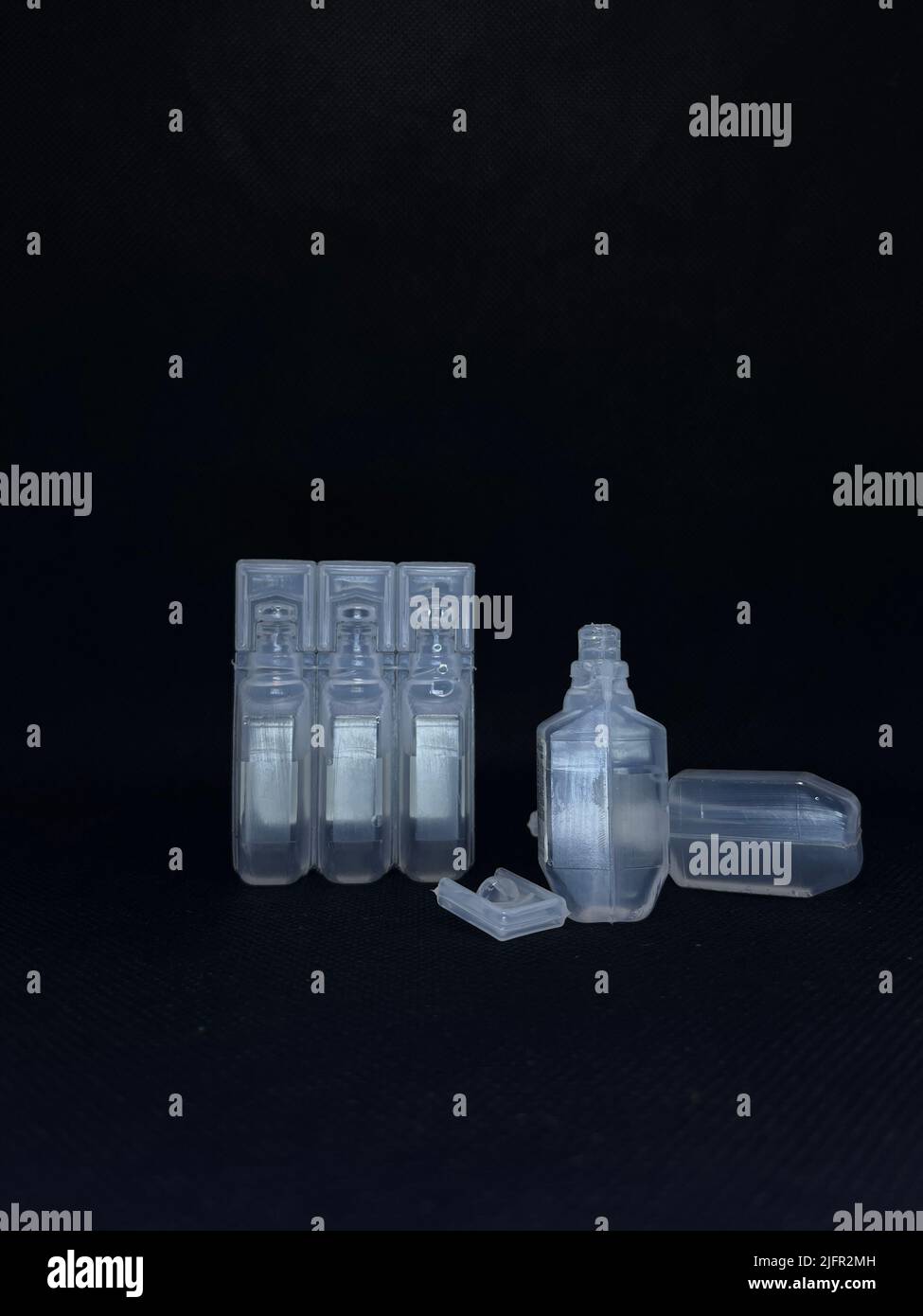 A vertical closeup of distilled water bottles isolated on a black ...