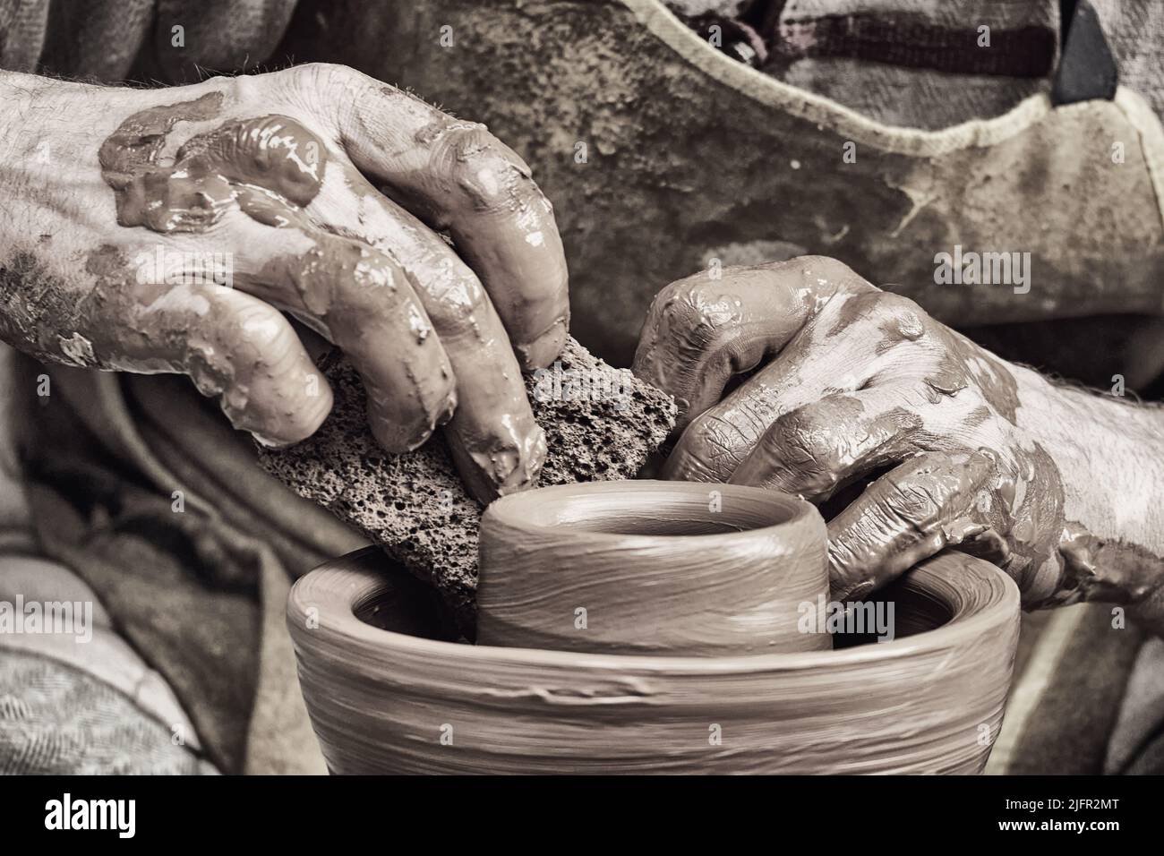 A man in old medieval Byzantine clothes sits behind a vintage potter's ...