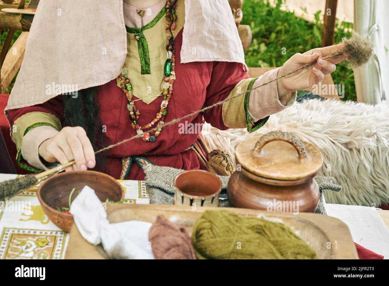 A woman in ancient Byzantine clothing makes yarn and sews from vintage ...
